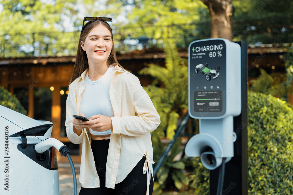 Sustainable urban commute with young woman pay electricity for EV ...