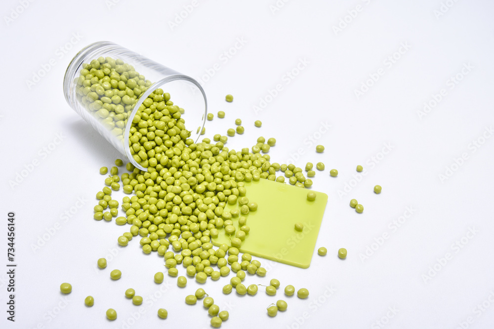 Guacamole color masterbatch granules spilled from a shot glass on a ...