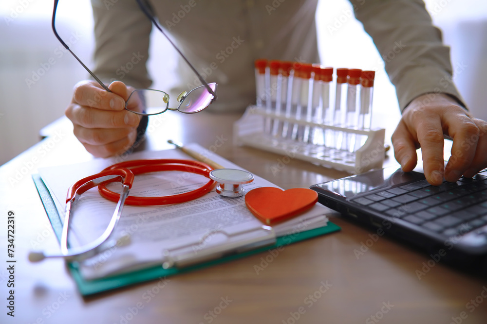 Doctor at his desk in the clinic's office. Stethoscope, test tubes ...