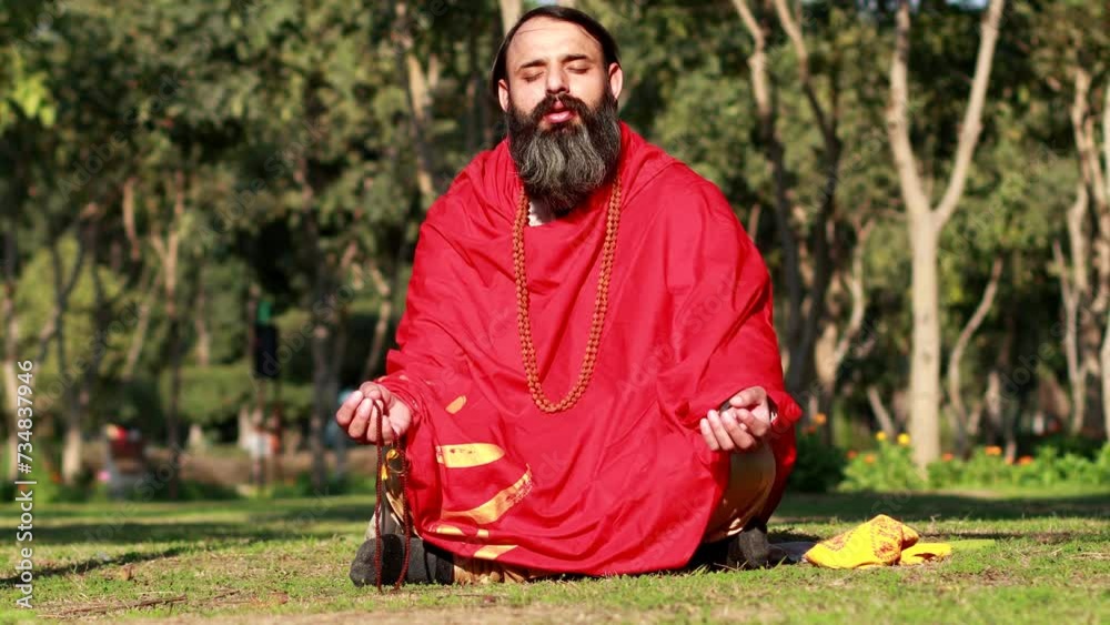Beard yogi of Indian ethnicity chanting mantras sitting in lotus ...