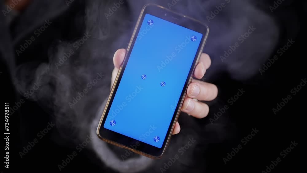Hand Holding a Mobile Phone with a Blue Screen on a Black Background in ...