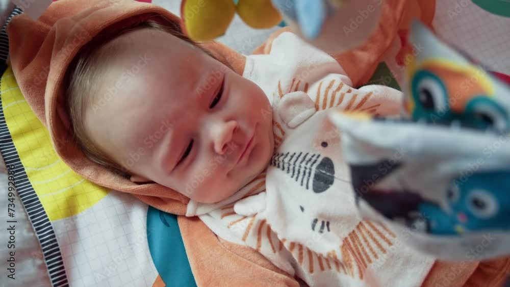 Vidéo Stock A baby gazing with intrigue at a colorful toy. The baby ...