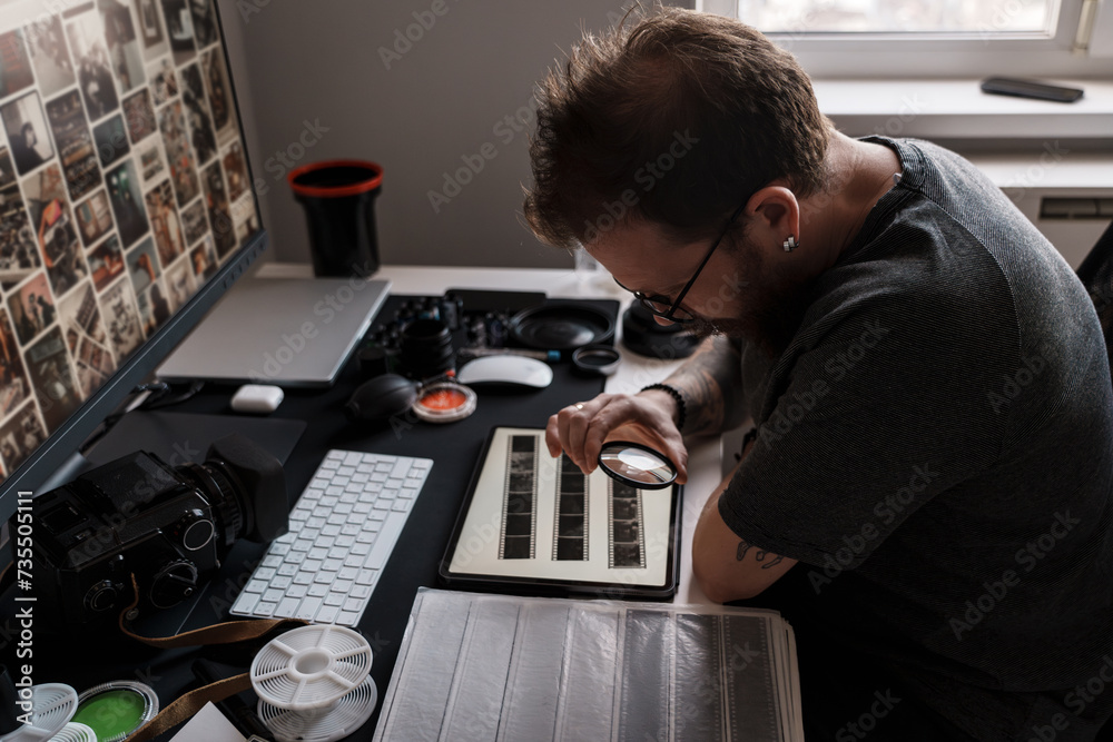 A photographer uses a magnifying glass for a detailed inspection of ...