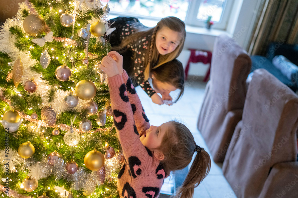 Little girl climbing on the top of her mothers shoulders to put ...