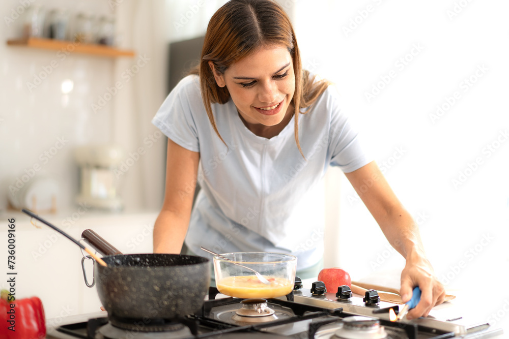 Housewife standing in kitchen fire stove with gas lighter at home. Mid ...