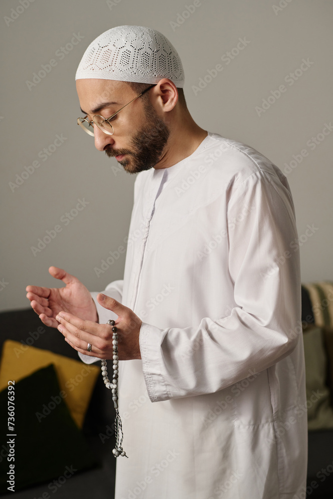Silent Muslim man in white kandora and skullcap holding rosary beads ...