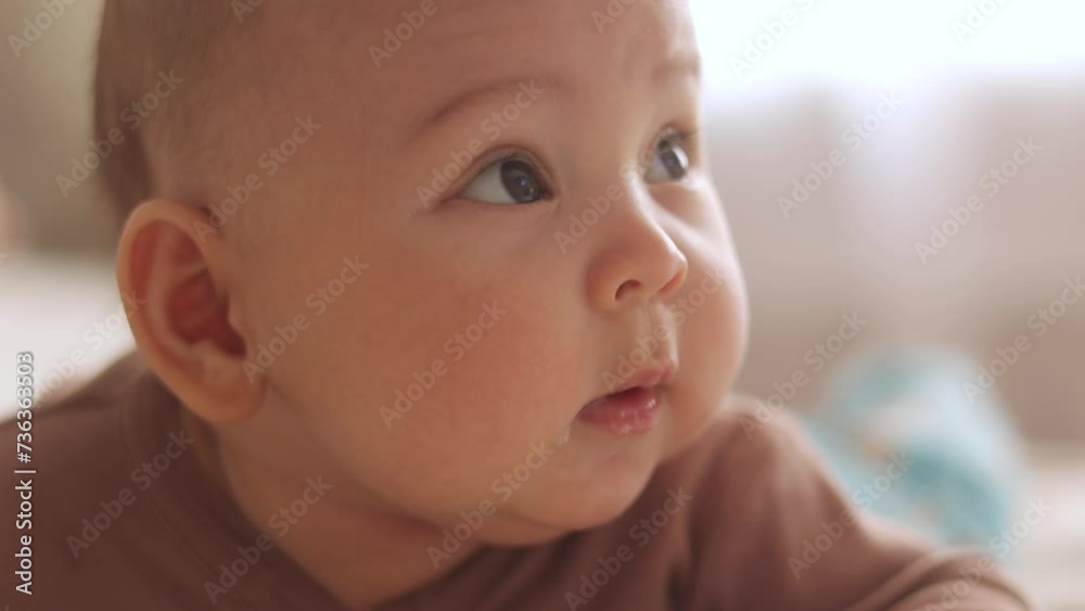 The baby looks to the side and observes the face in close-up in slow ...