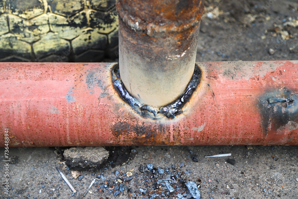 Welded tee joint with some defects. Two metal pipes welded together in ...