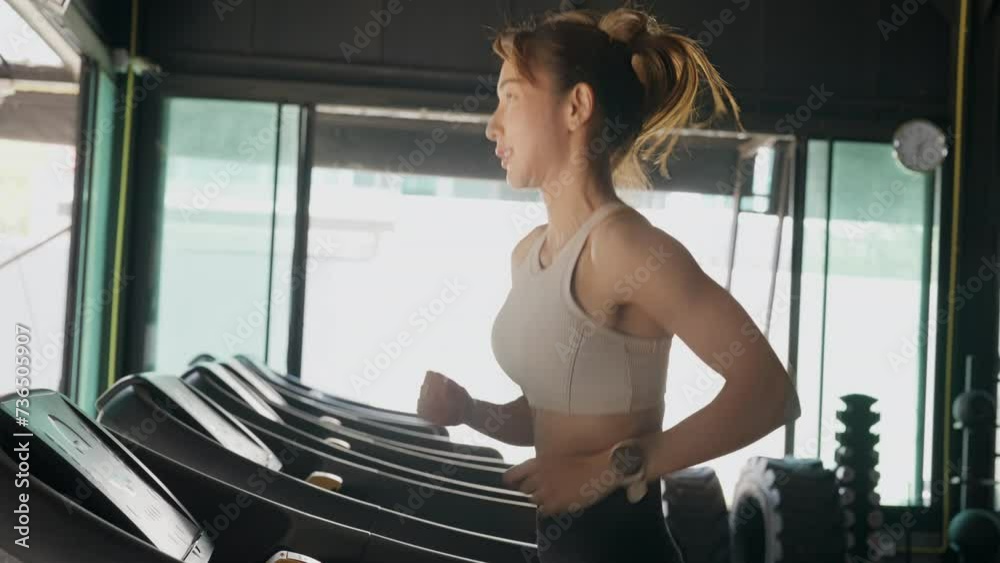 Woman Jogging on Treadmill in Modern GymSide view of a young woman with ...