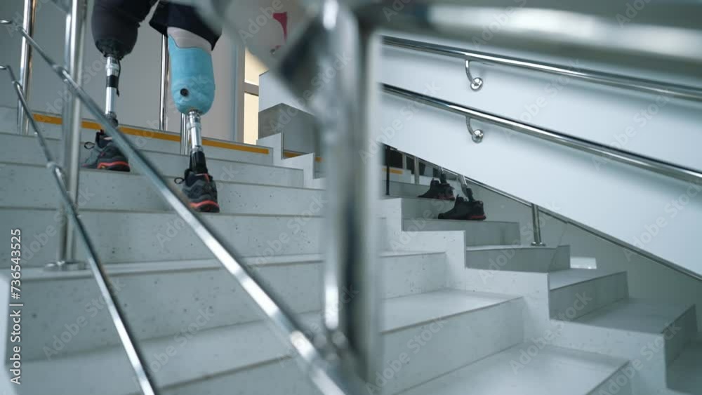 A disabled person with two prosthetic legs is undergoing rehabilitation ...