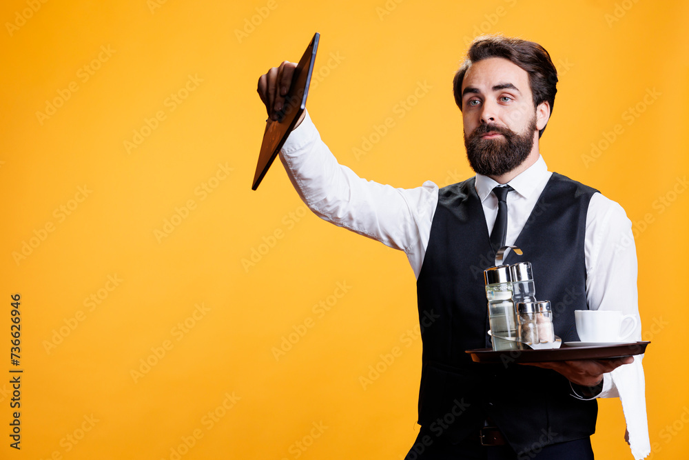 Young restaurant server giving menu to clients at table, pretending to ...