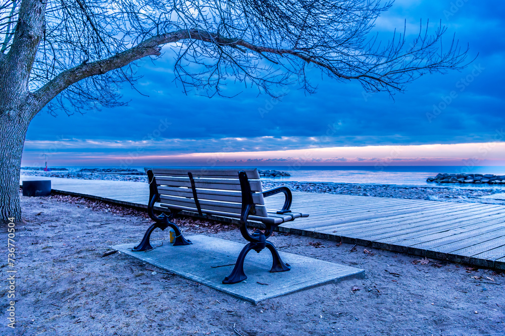park bench beside wooden boardwalk on beach at sunrise blue hour in ...