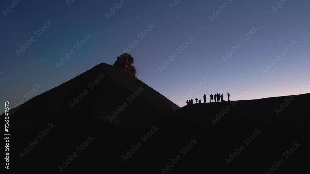Cinematic aerial orbit captures a group on Fuego volcano's ridge as it ...