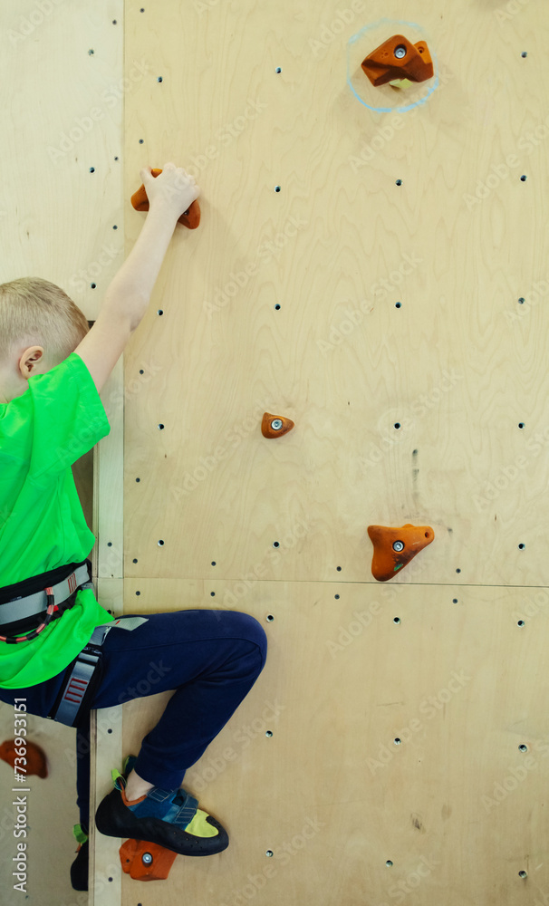 Rock climbing for children. Blond boy in a green shirt is climbing ...
