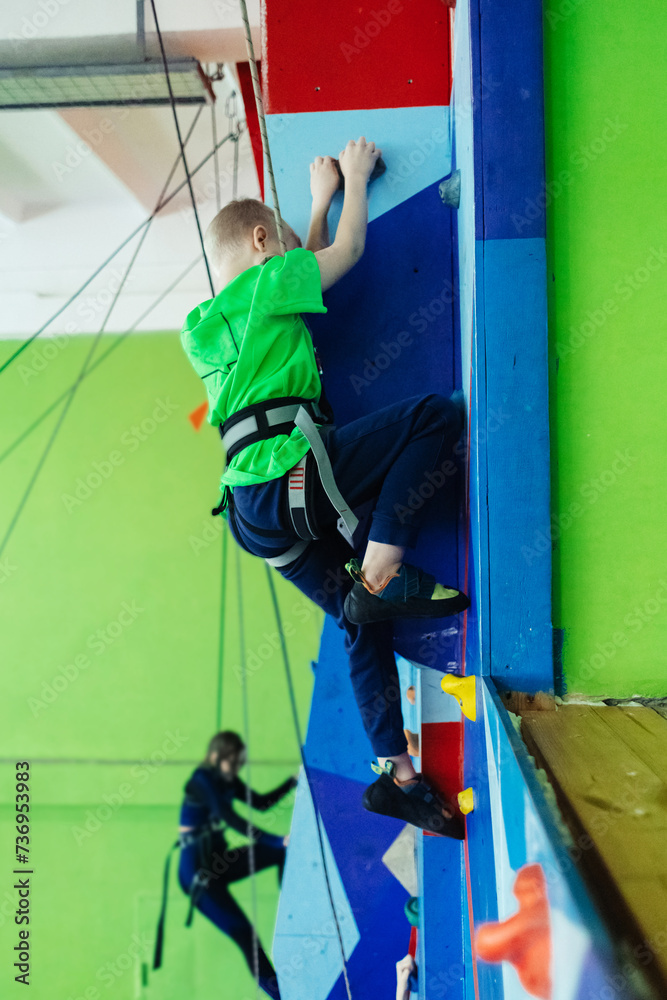 Rock climbing for children. Blond boy in a green shirt is climbing ...