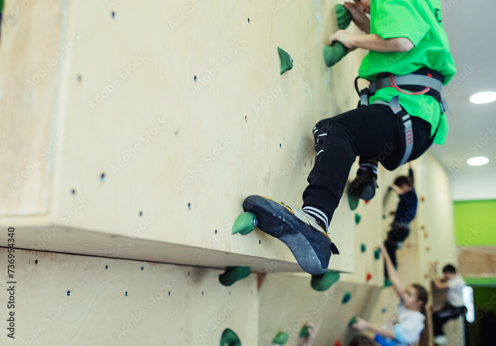 Rock climbing for children. Blond boy in a green shirt is climbing ...
