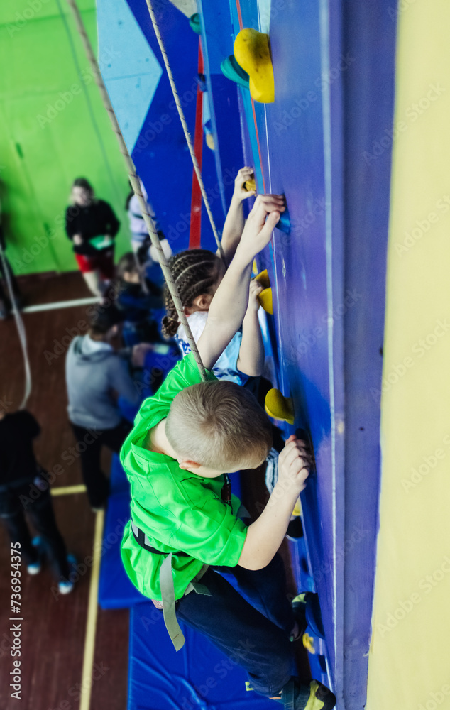 Rock climbing for children. Blond boy in a green shirt is climbing ...
