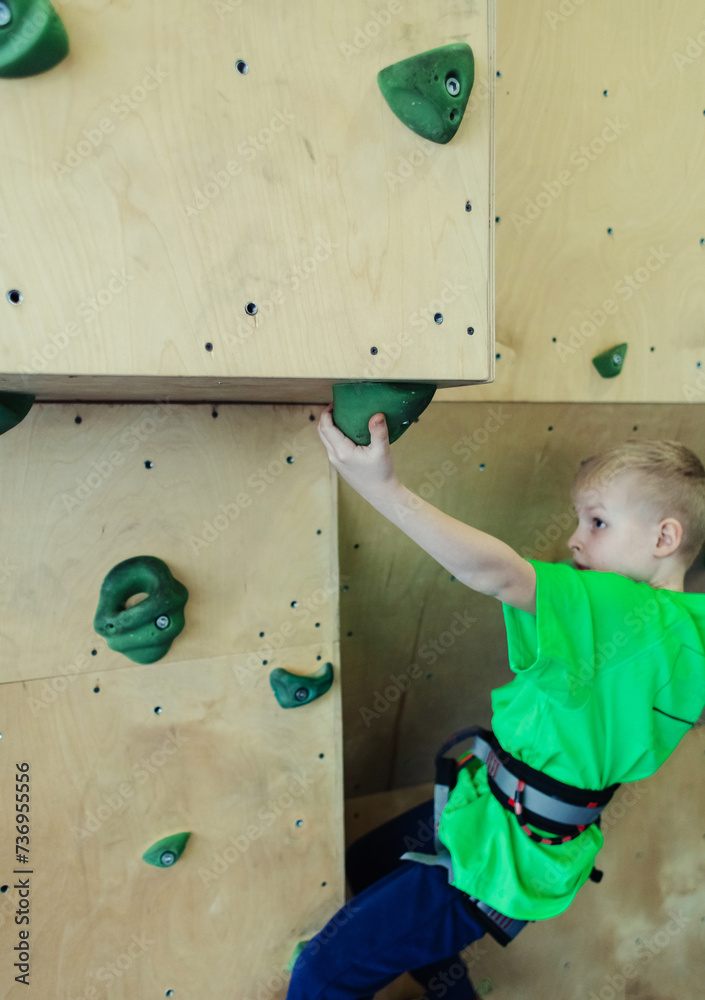 Rock climbing for children. Blond boy in a green shirt is climbing ...