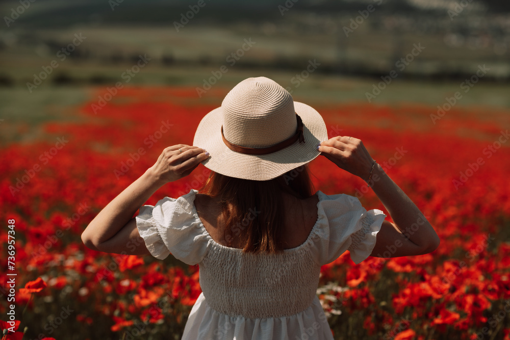 Field poppies woman. Happy woman in a white dress and hat stand through ...