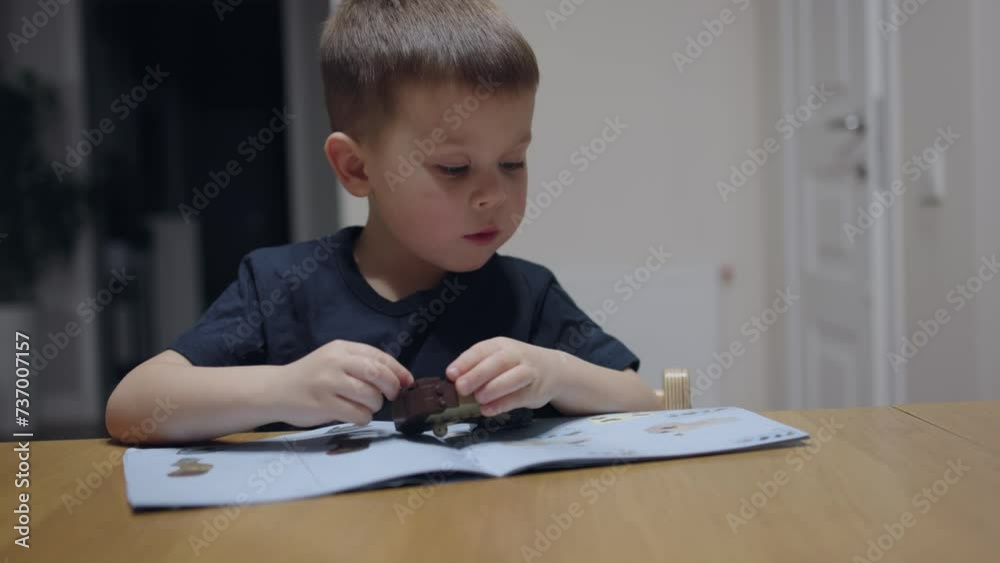 little child boy collects small plastic parts constructor, reads ...