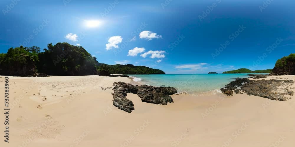 Diapela Beach with inshore waves with bubbles on sandy beach and rocks ...