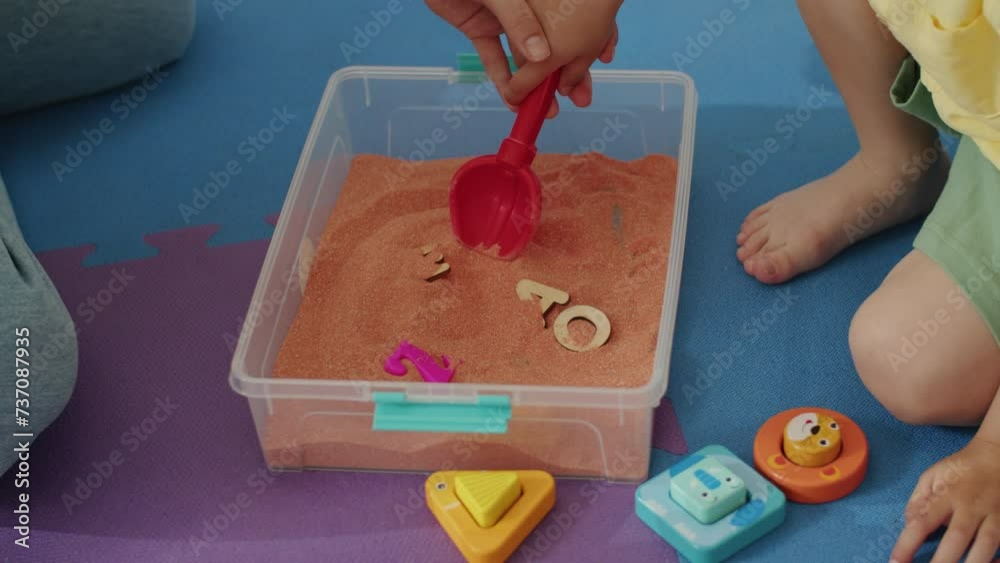 Therapist and child using a sensory sand tray for tactile learning ...