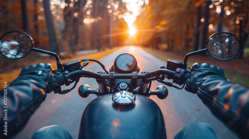 Biker's perspective of riding a motorcycle down a forest road at sunset ...