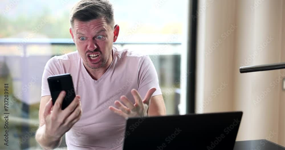 Vidéo Stock Angry man siting at table and yelling into screen of mobile ...