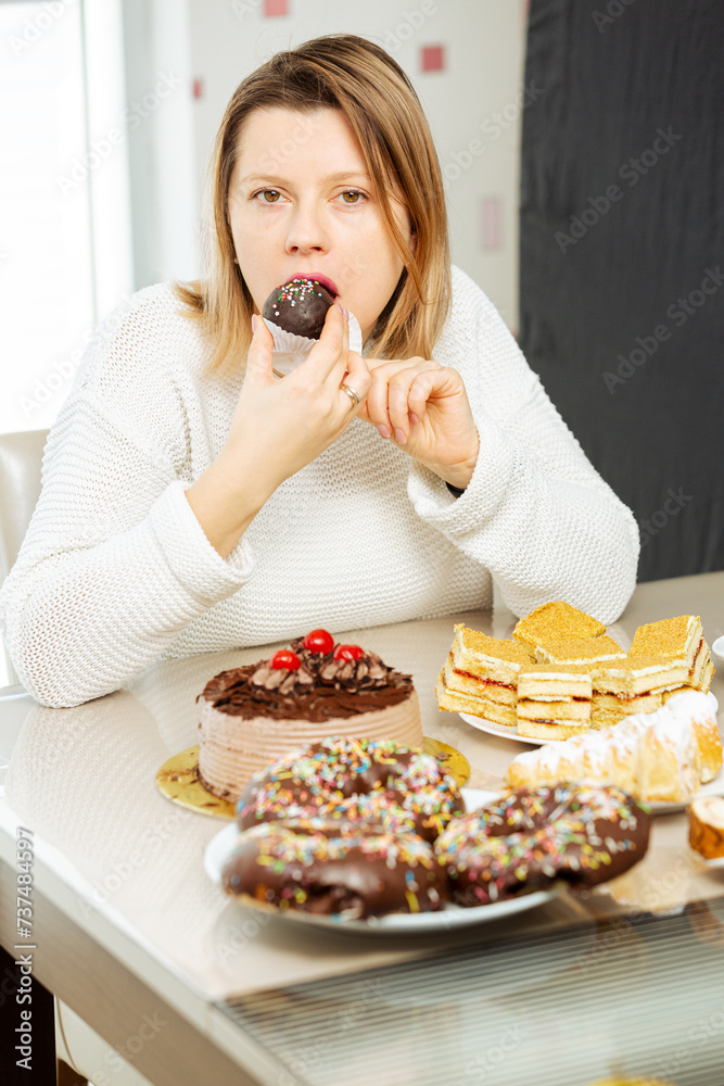 Woman eating pastry with cream, picking what to eat sitting beside ...