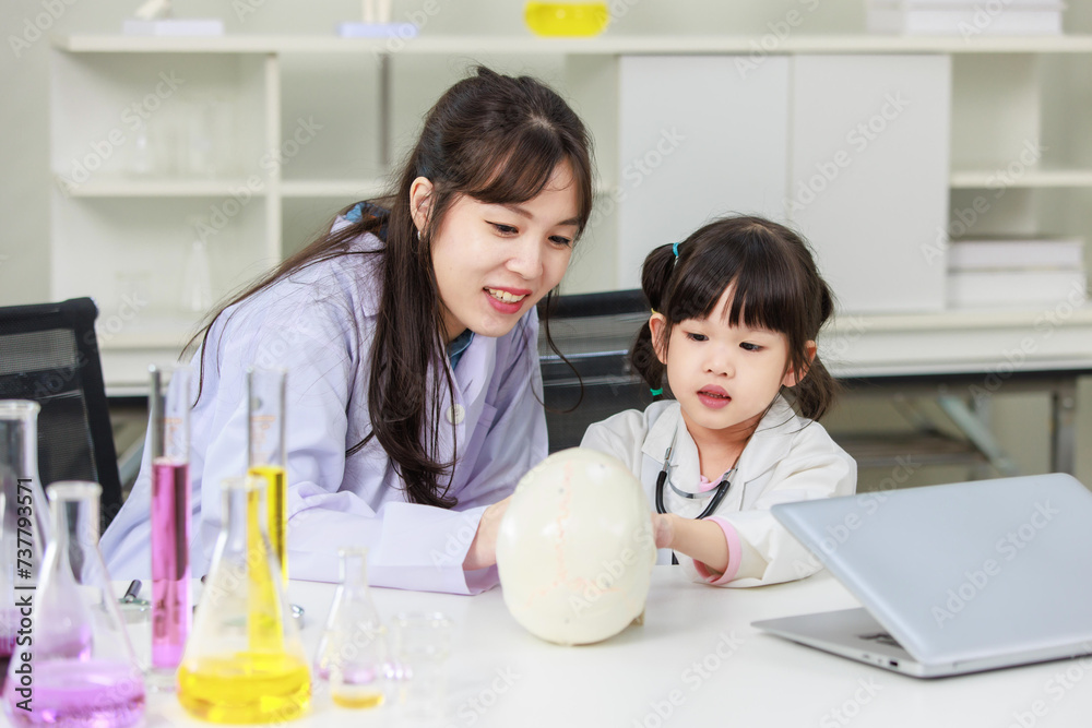 Asian woman doctor physiotherapist explains human fake skeleton skull ...