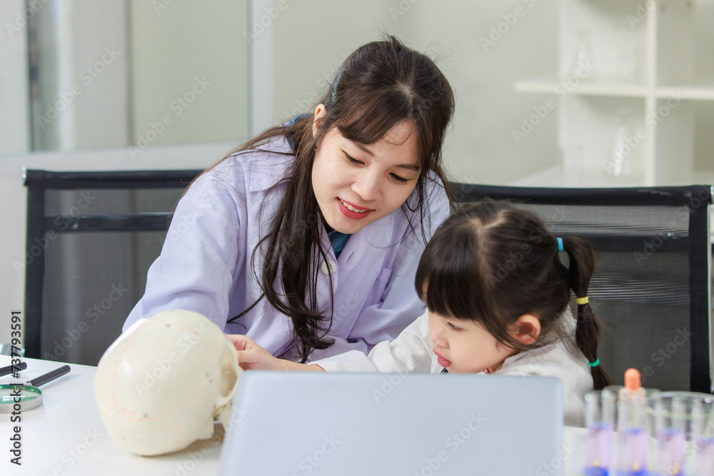 Asian woman doctor physiotherapist explains human fake skeleton skull ...