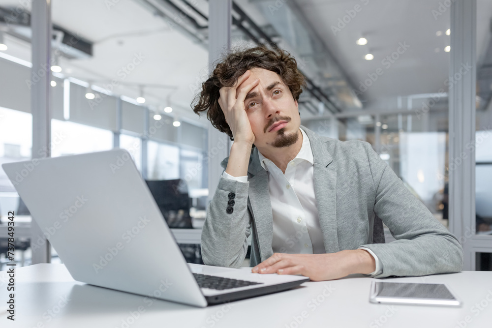 Stressed young businessman with curly hair pondering solutions at his ...