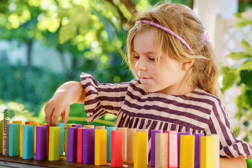Little preschool girl playing board game with colorful bricks domino ...