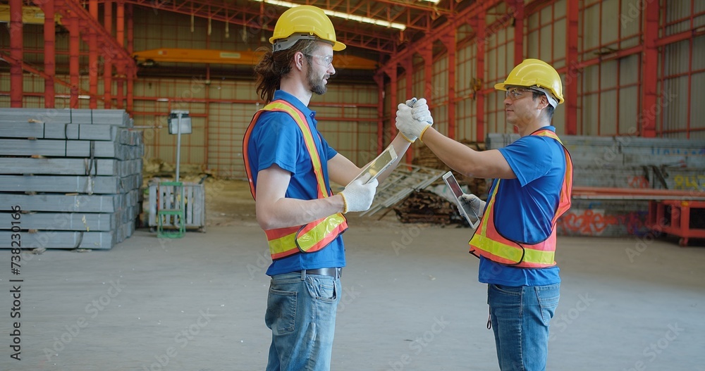 Two construction engineer workers in hard hats and vests engage in a ...