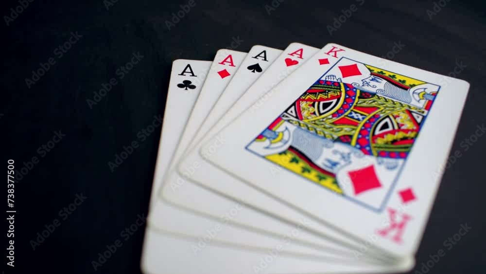 Hand of cards. Four aces and a king. Moving left to right. Black table ...