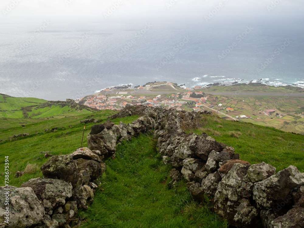 Walking route between the stone walls dividing the green grass fields ...