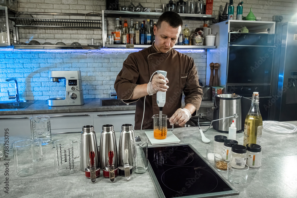 Chef in uniform engages in cooking process in modern kitchen ...