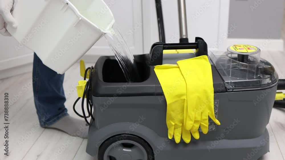 A cleaning company worker pours clean water from a white bucket into ...