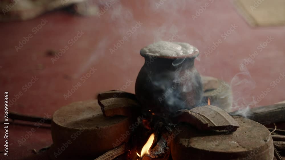 Clay pot boiling milk over wood fire, Vesak fest rituals. Smoke rises ...