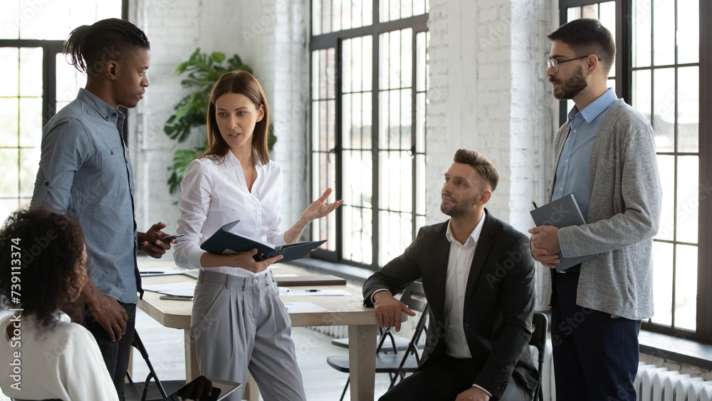 Top manager talking to employees in modern loft workspace, instructing ...