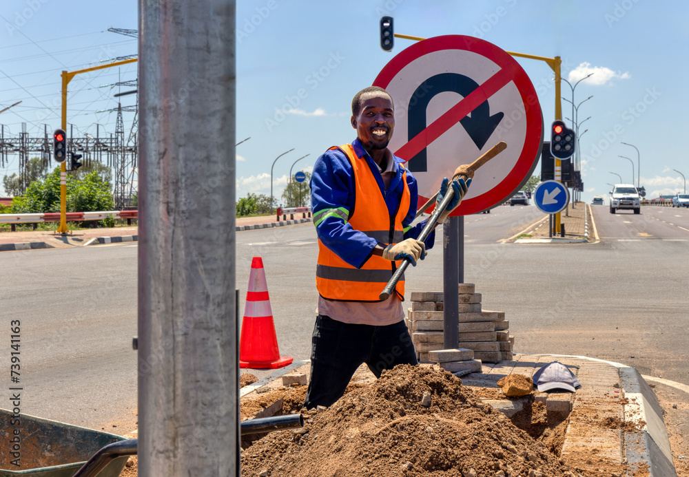african american worker with a pickaxe digging a ditch in the highway ...