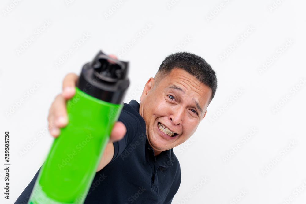 A cowardly middle-aged Asian man showing a comical expression of fear while using insecticide ...
