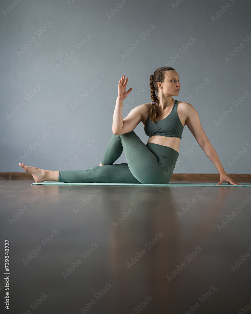 woman does stretching, yoga in gym on mat. Half fish pose. Ardha ...