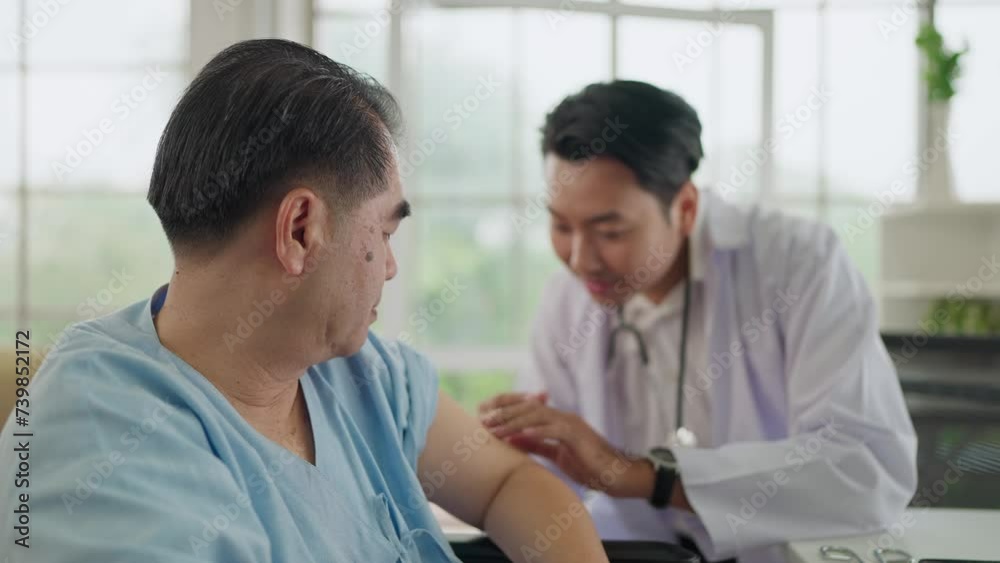 Young asian male doctor giving inject to senior patient in wheelchair. Doctor injects flu ...