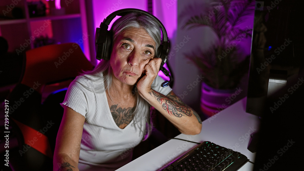 Mature, grey-haired woman gamer, in serious gaming mode, streaming live ...