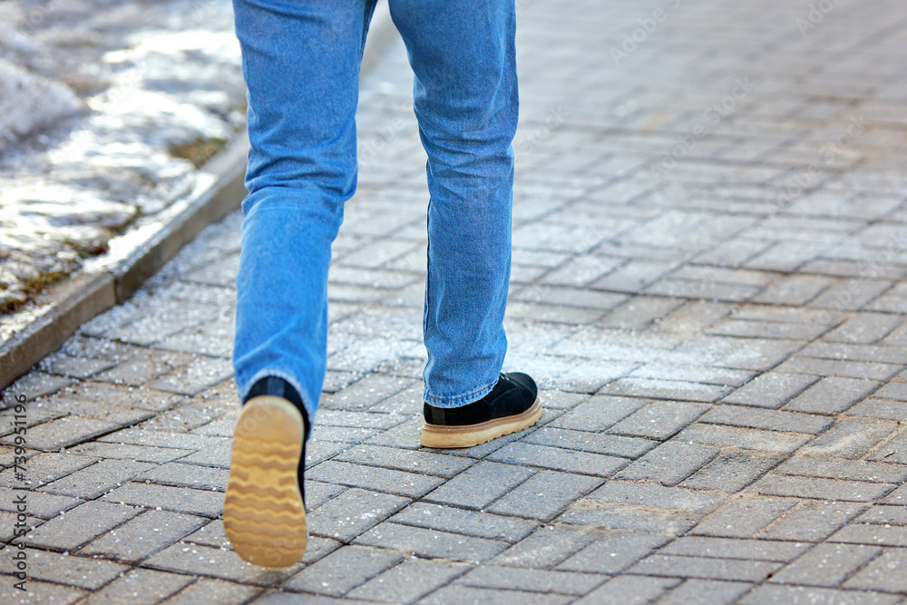Man walking on sidewalk covered with rock salt and sand, prevent ...