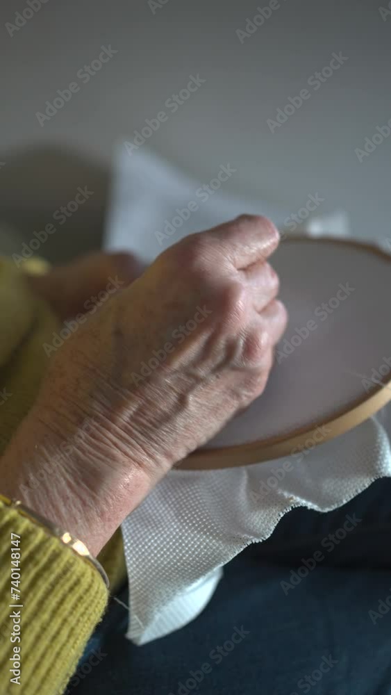 Detail of finger pointing cross-stitch drawing, hands of seventy-year ...