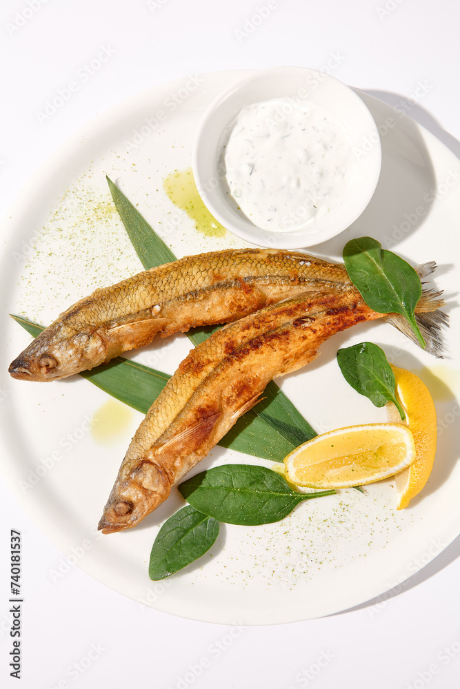 Top view of fried vendace fish with lemon and sour cream on white ...
