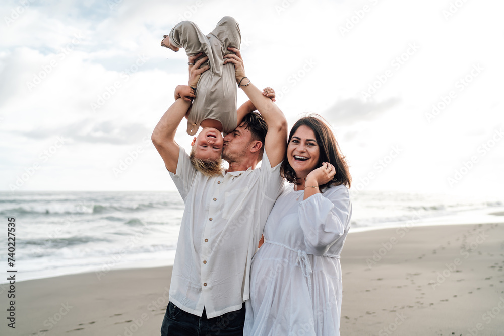 Exuberant family enjoying a beach outing: Father lifts up laughing ...