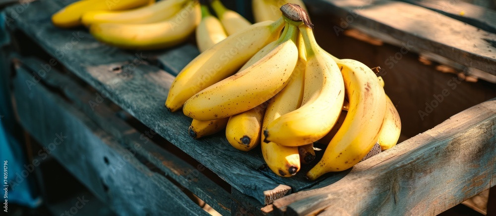A cluster of bananas is displayed on a rustic wooden table, showcasing ...